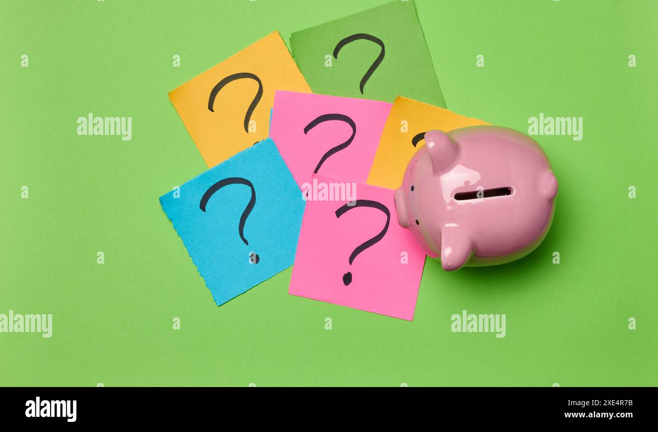 Ceramic piggy bank and stickers with drawn question marks on a green ...