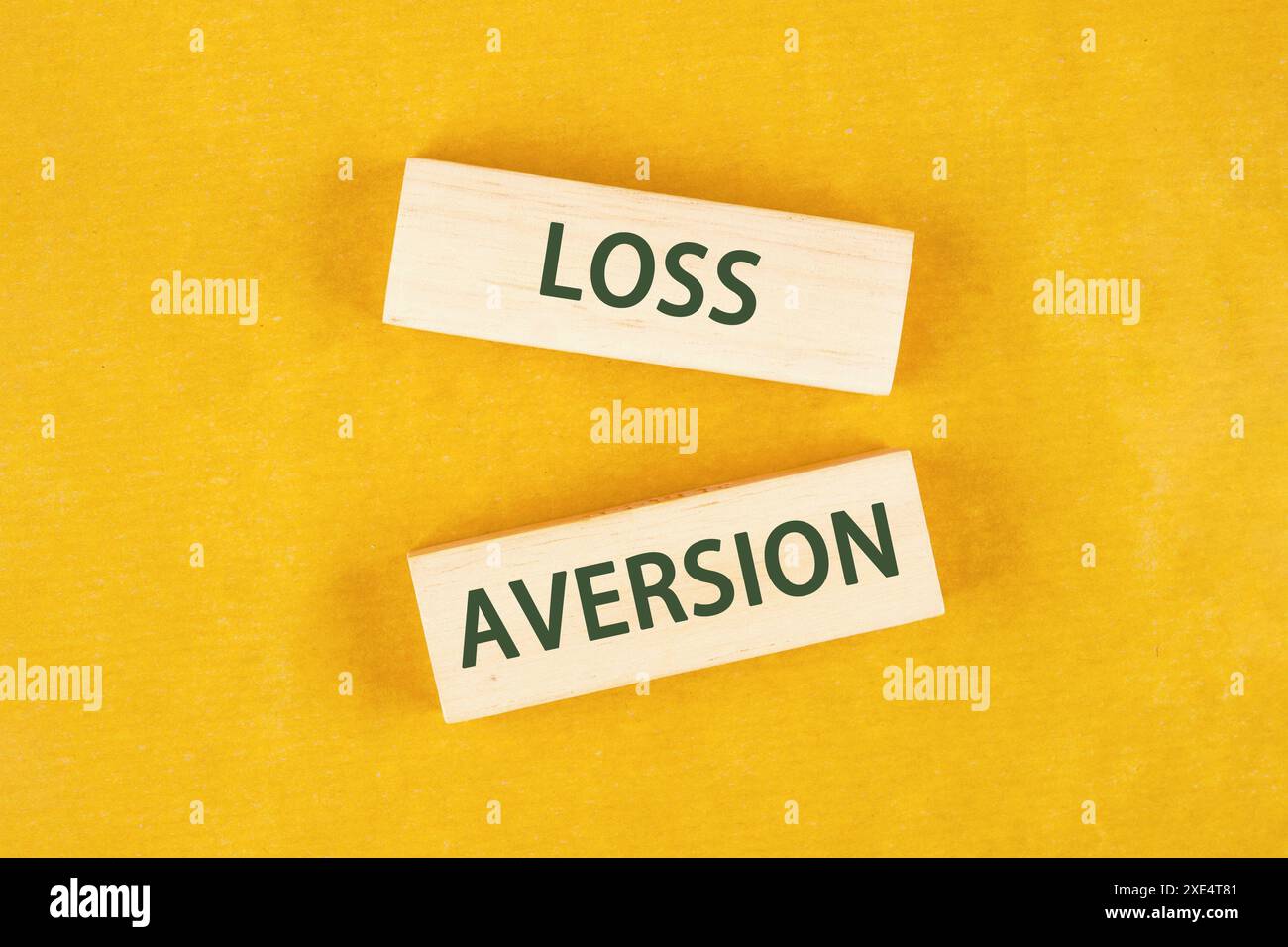 LOSS AVERSION text written on wooden blocks on a bright yellow mustard ...