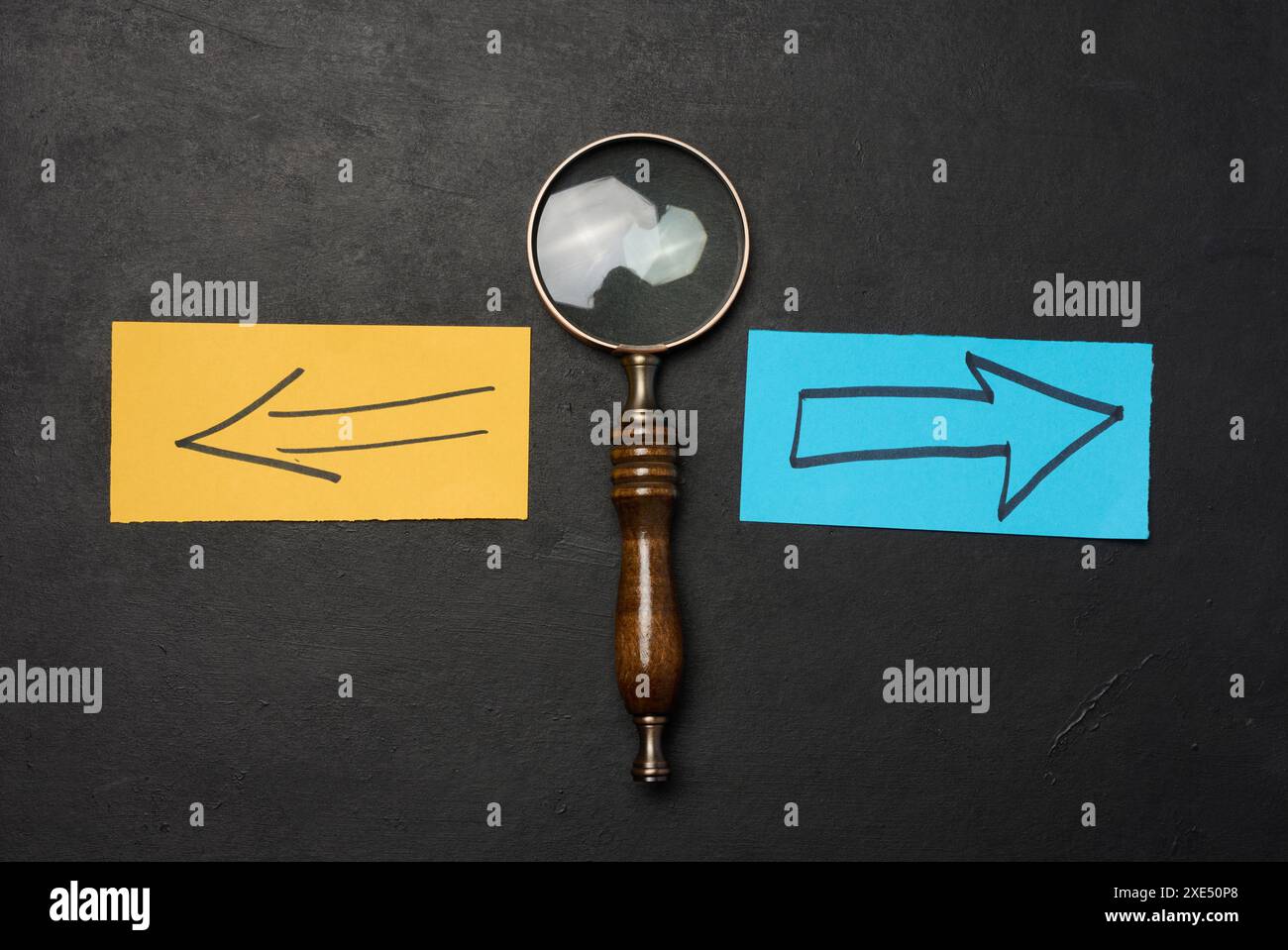 Magnifying glass and two paper sheets with arrows pointing in different ...