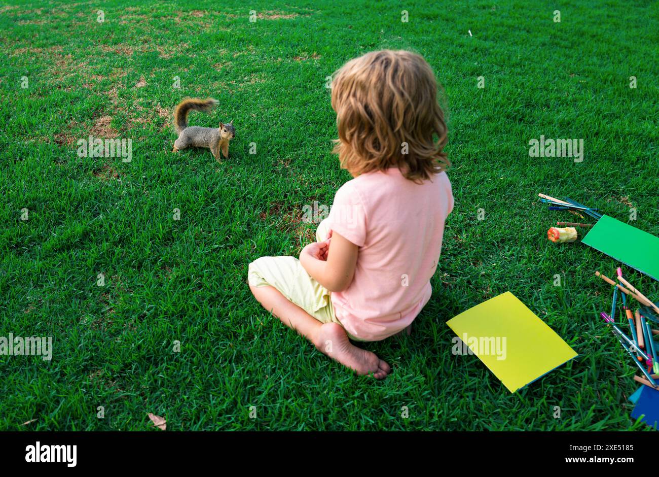 Child pupil sitting on lawn in park, play with squirrel. Studies and ...
