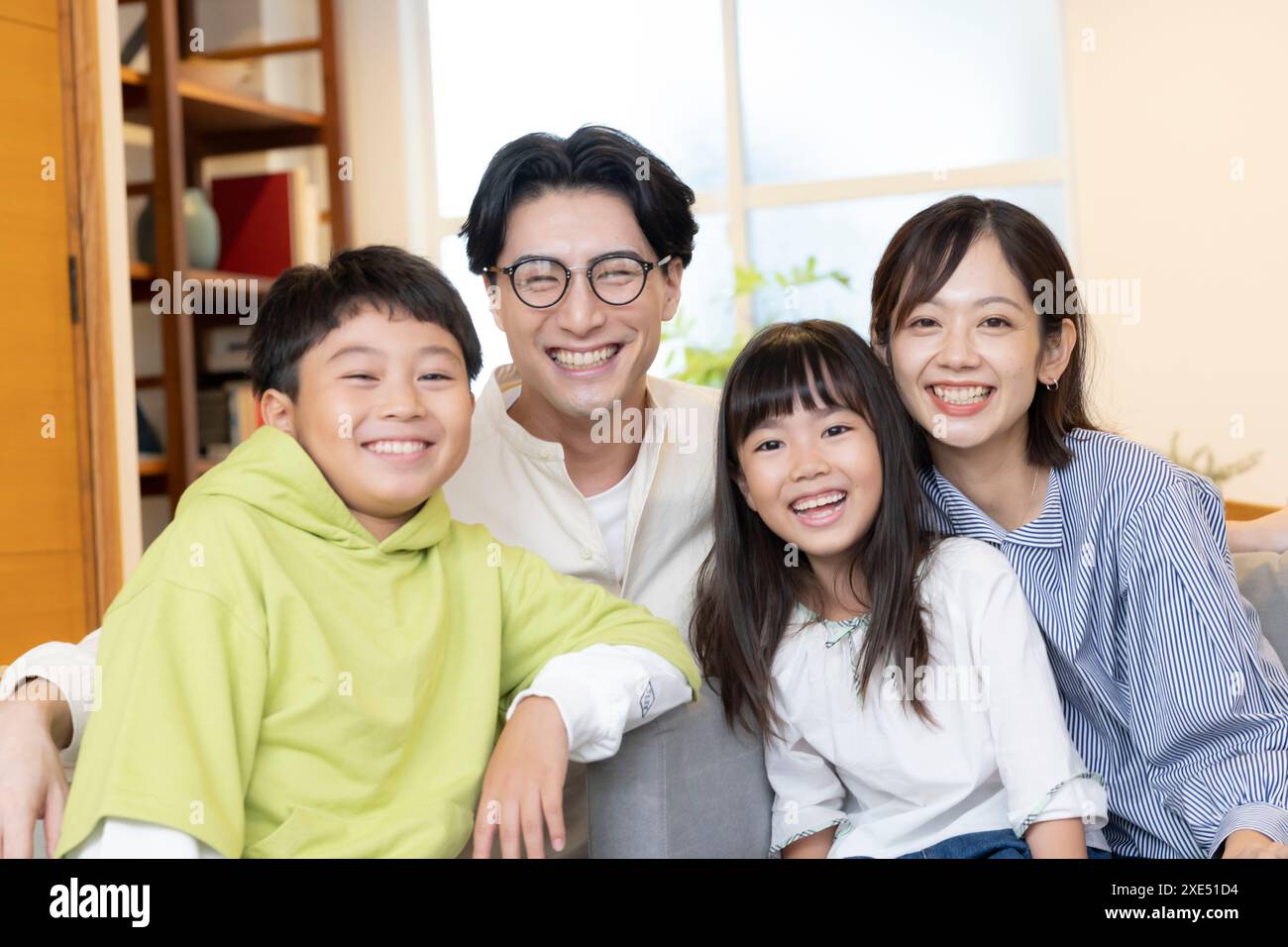 Family of four sitting on a sofa and smiling Stock Photo - Alamy