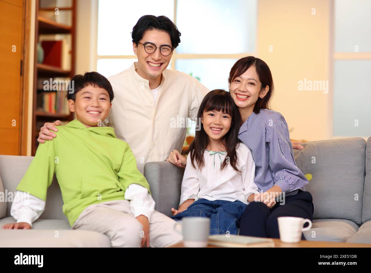 Family of four sitting on a sofa and smiling Stock Photo - Alamy