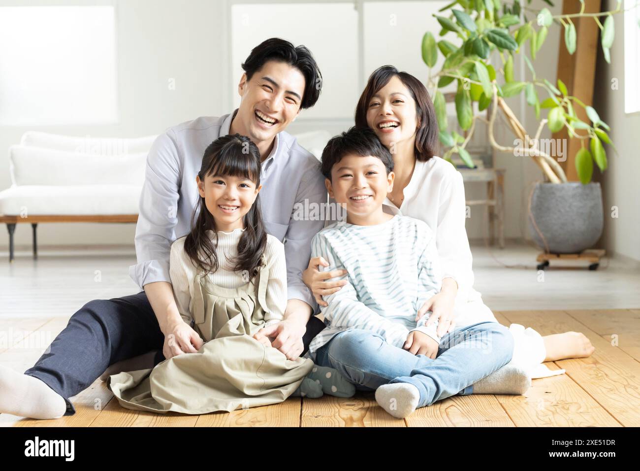 Family of four sitting on the floor and smiling Stock Photo - Alamy