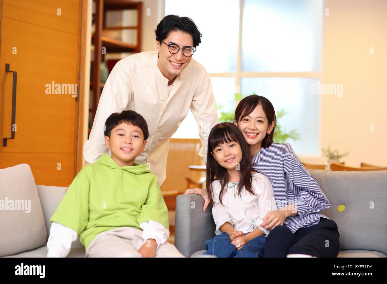 Family of four sitting on a sofa and smiling Stock Photo - Alamy