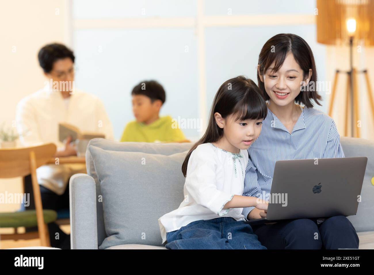 Family of four opening laptop and books Stock Photo - Alamy