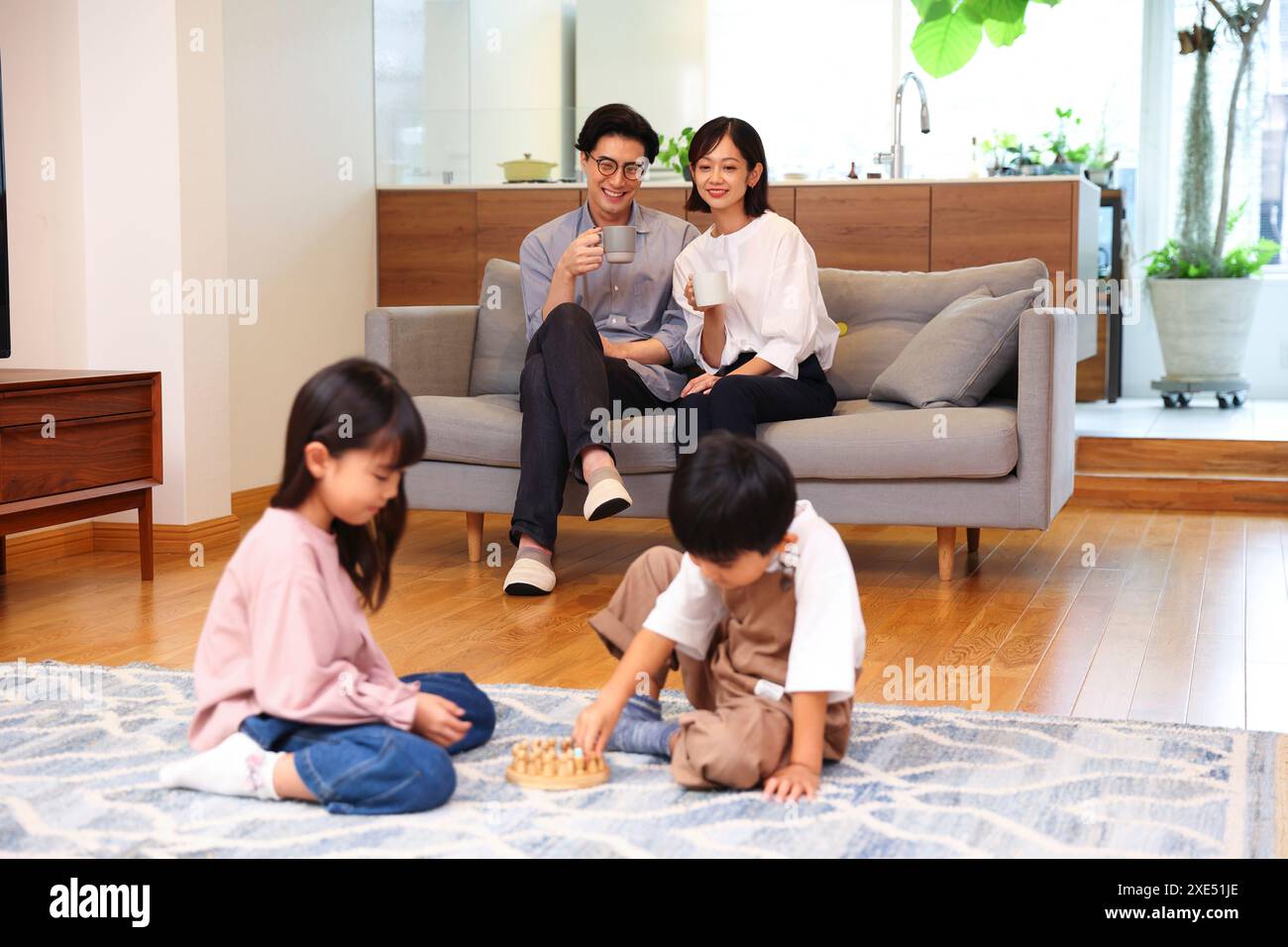 Family of four happy around the sofa Stock Photo - Alamy