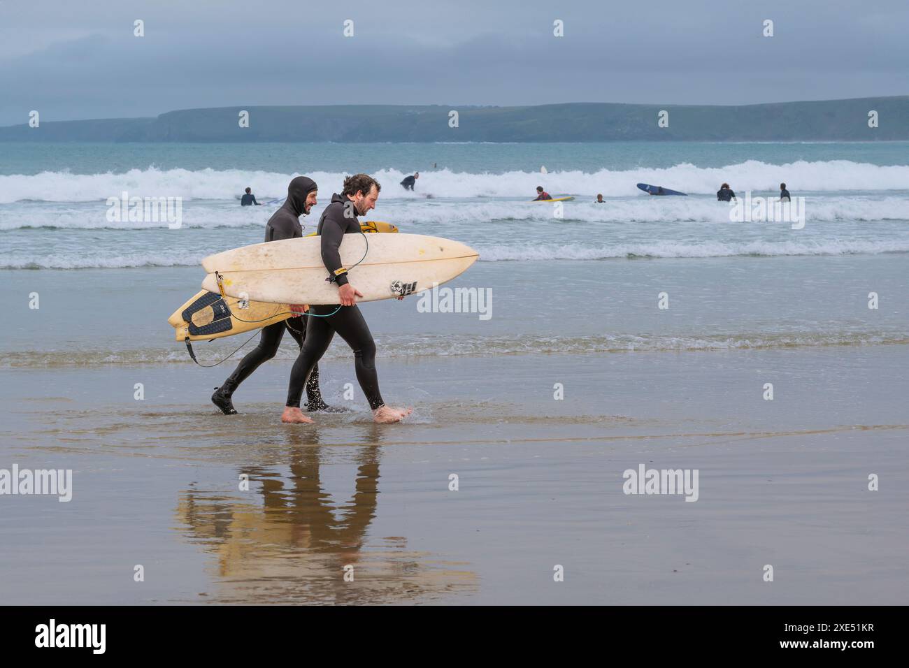 Two surfing friends carrying their surfboards walking along the ...