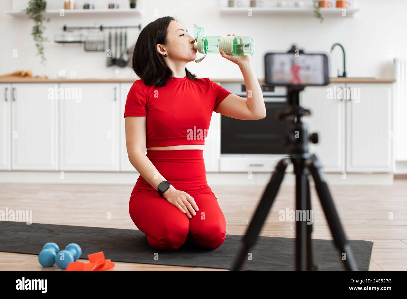 Woman recording fitness video at home drinking water Stock Photo - Alamy