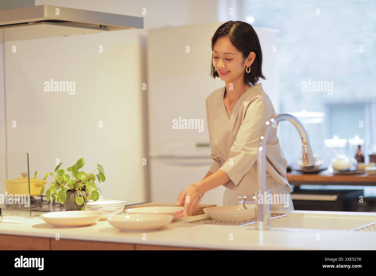 Woman in her 30s putting away dishes in the kitchen Stock Photo - Alamy