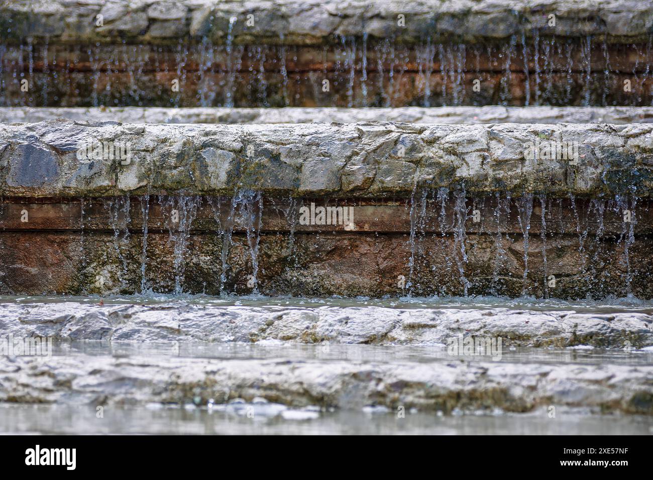 Water cascading down stone steps in city park. Water is falling in a ...