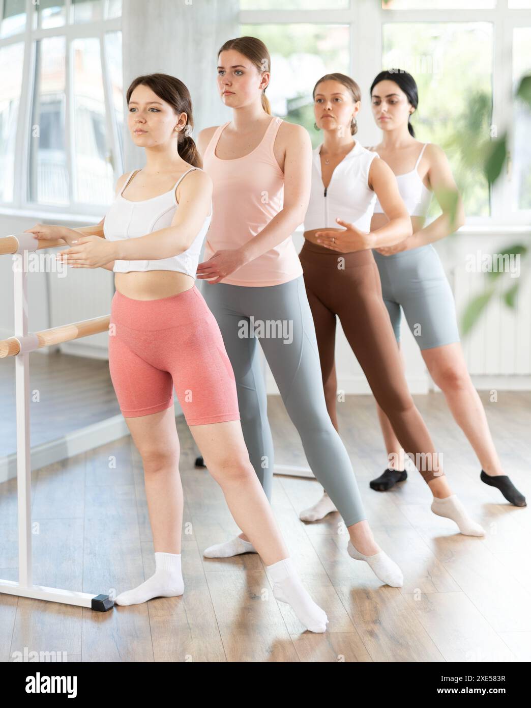 Group of positive young girls standing in row together while doing ...