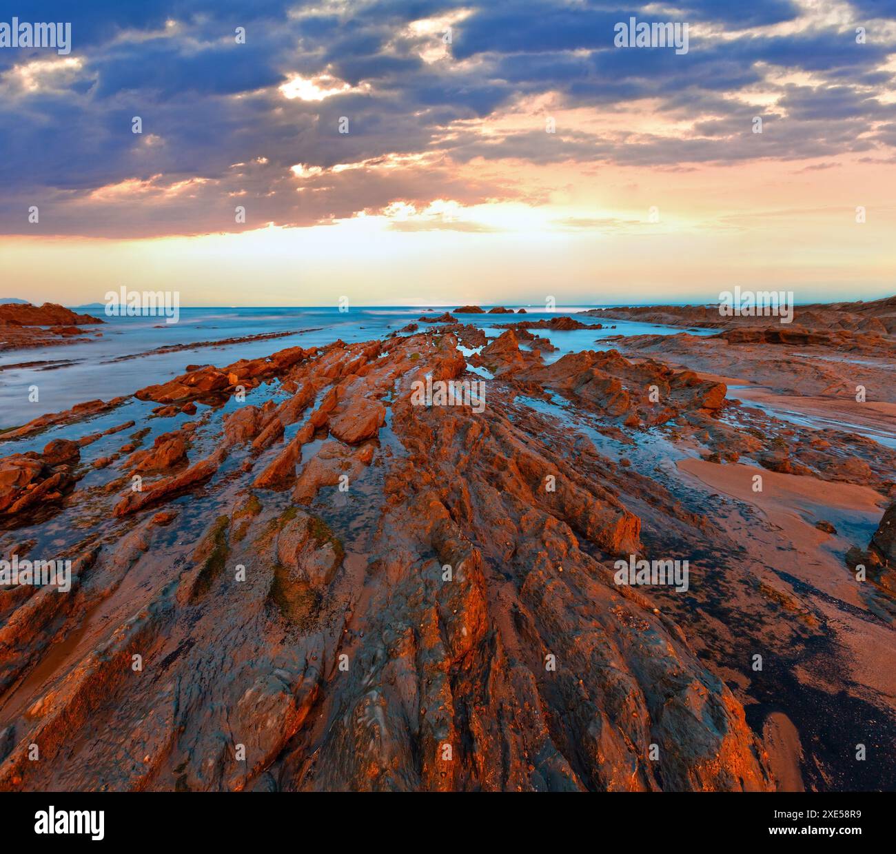 Twilight ocean coast with ribbed stratiform rock Stock Photo - Alamy