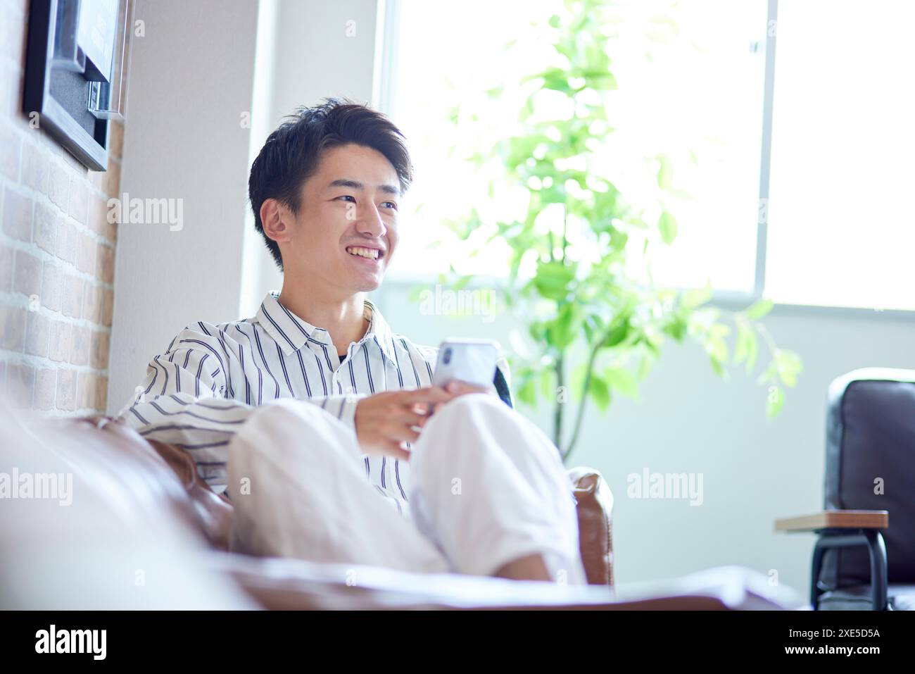 Young Japanese man relaxing in living room Stock Photo - Alamy