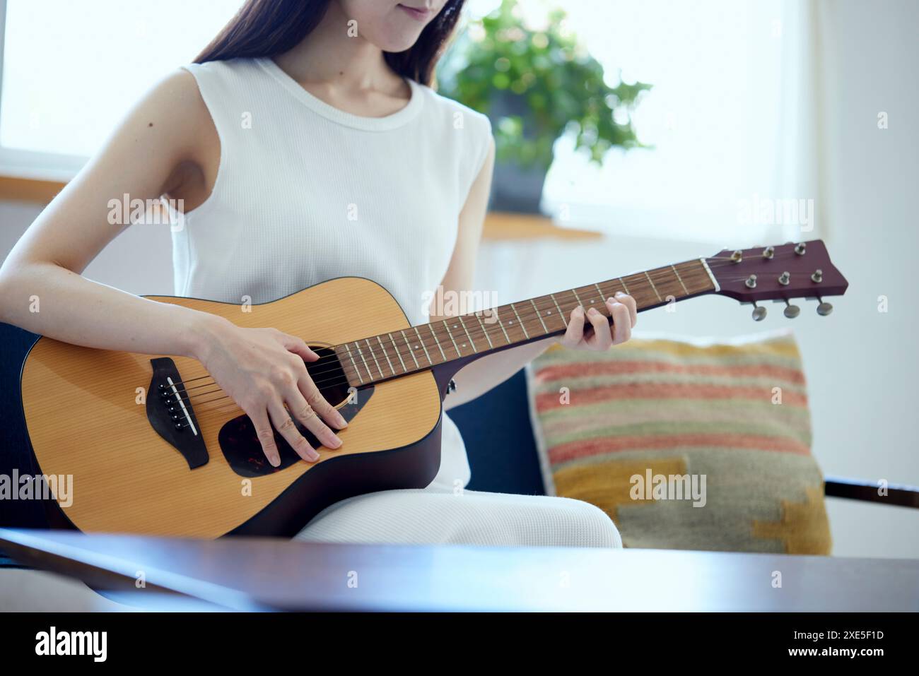 Japanese woman playing guitar on sofa Stock Photo - Alamy