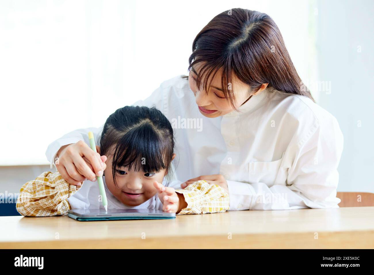 Parent and child studying using pen and tablet in living room Stock ...