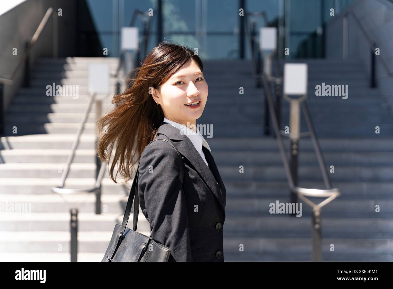 Woman in suit looking back and smiling Stock Photo - Alamy