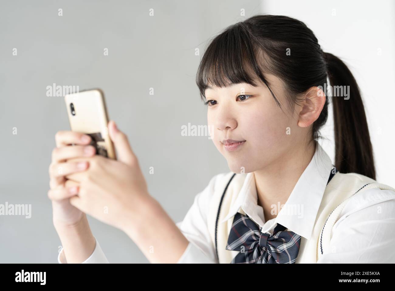 Female student in school uniform looking at her phone Stock Photo - Alamy