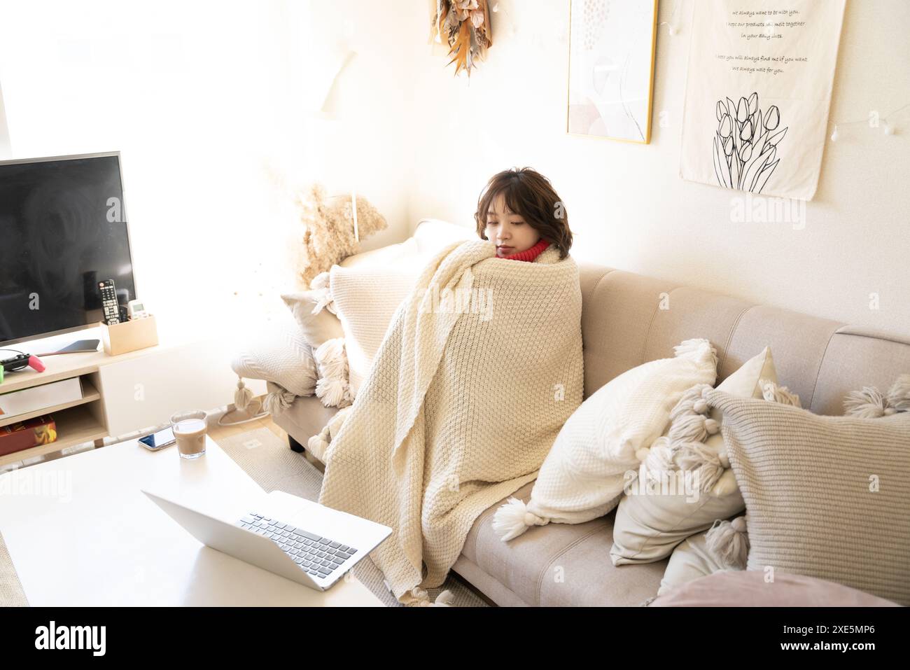Woman wrapped in blanket in room looking at computer Stock Photo - Alamy