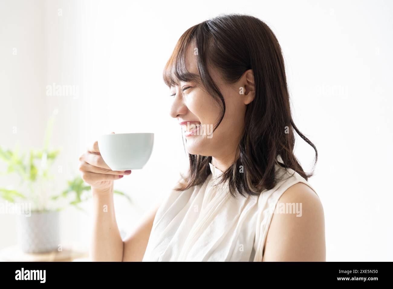 Woman laughing while drinking tea Stock Photo - Alamy