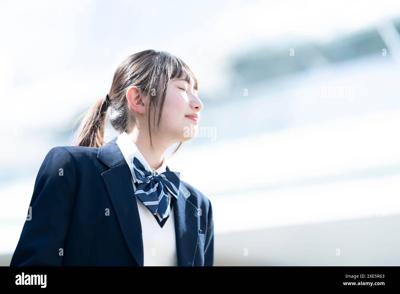 Schoolgirl in uniform with her eyes closed outdoors Stock Photo - Alamy