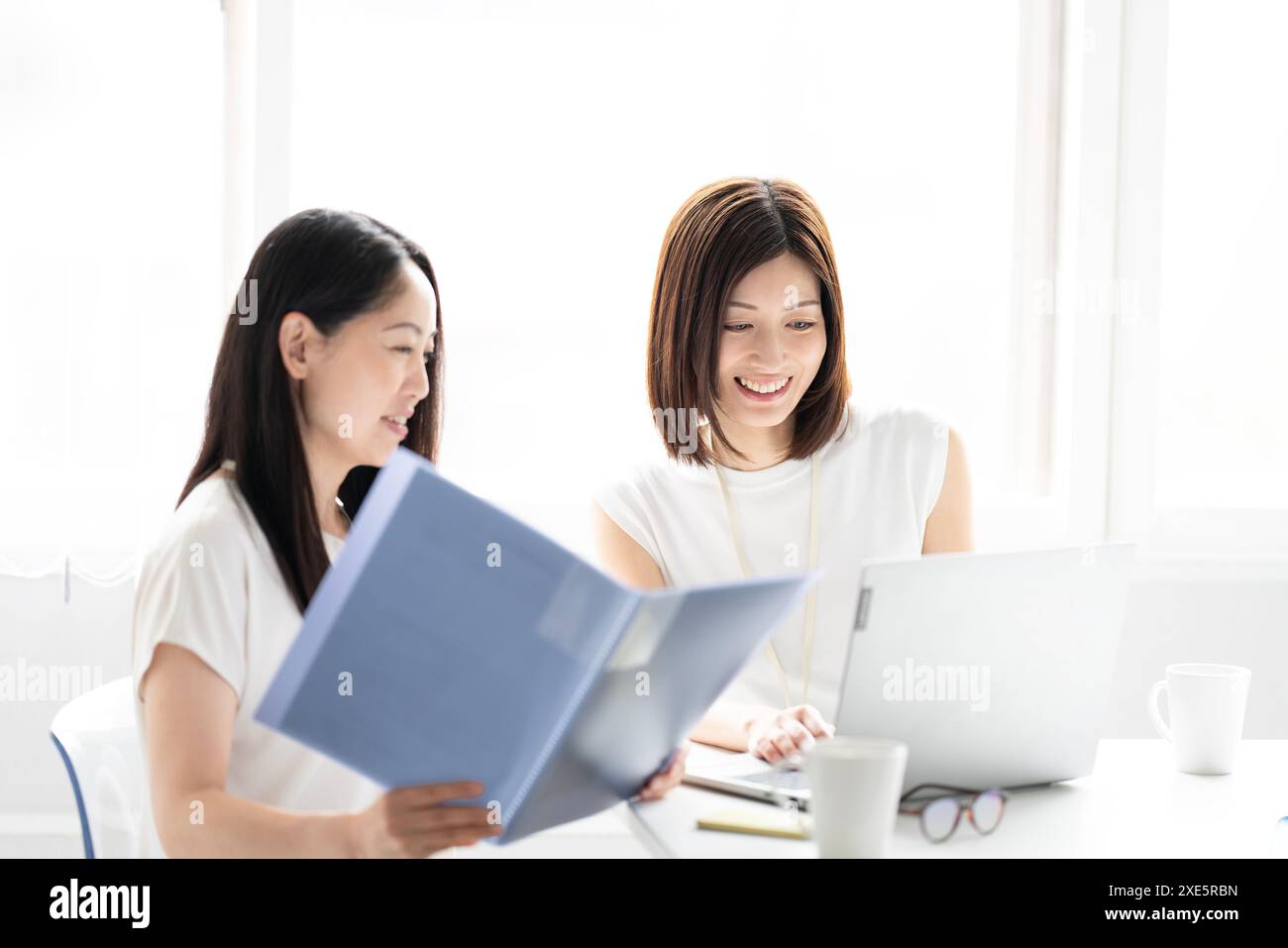 Two women working with computer open in office Stock Photo - Alamy