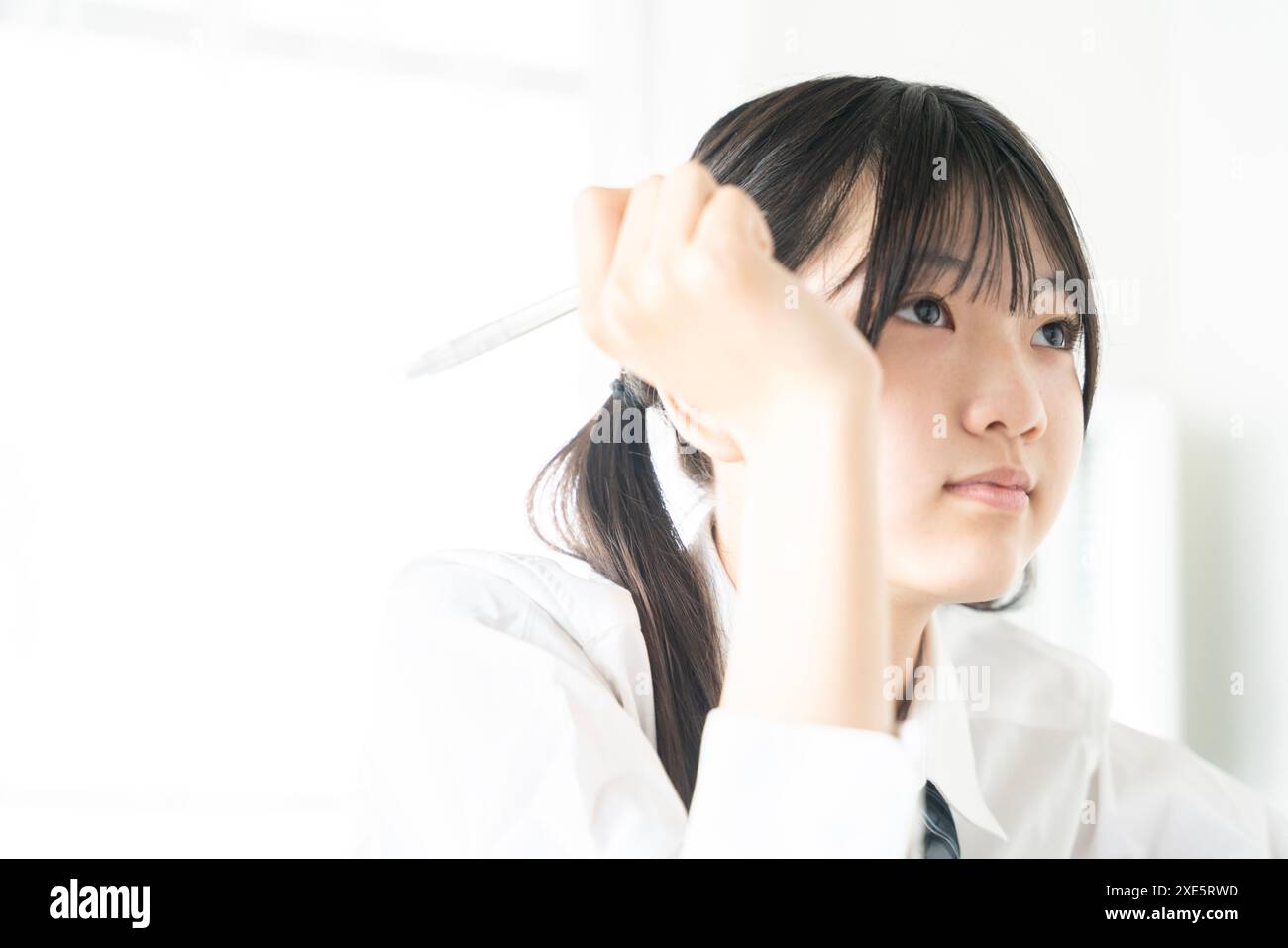 Schoolgirl in school uniform studying with pen in hand Stock Photo - Alamy