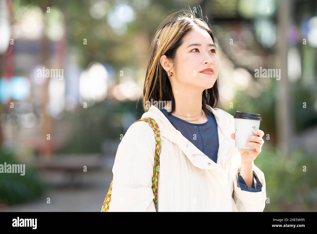 Woman walking with coffee in hand in the city Stock Photo - Alamy