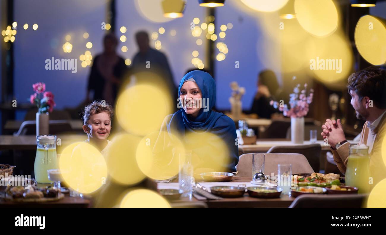 In a modern restaurant, an Islamic couple and their children joyfully ...