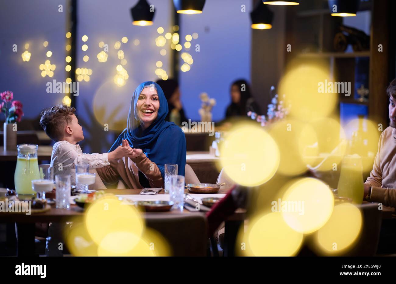 In a modern restaurant, an Islamic couple and their children joyfully ...