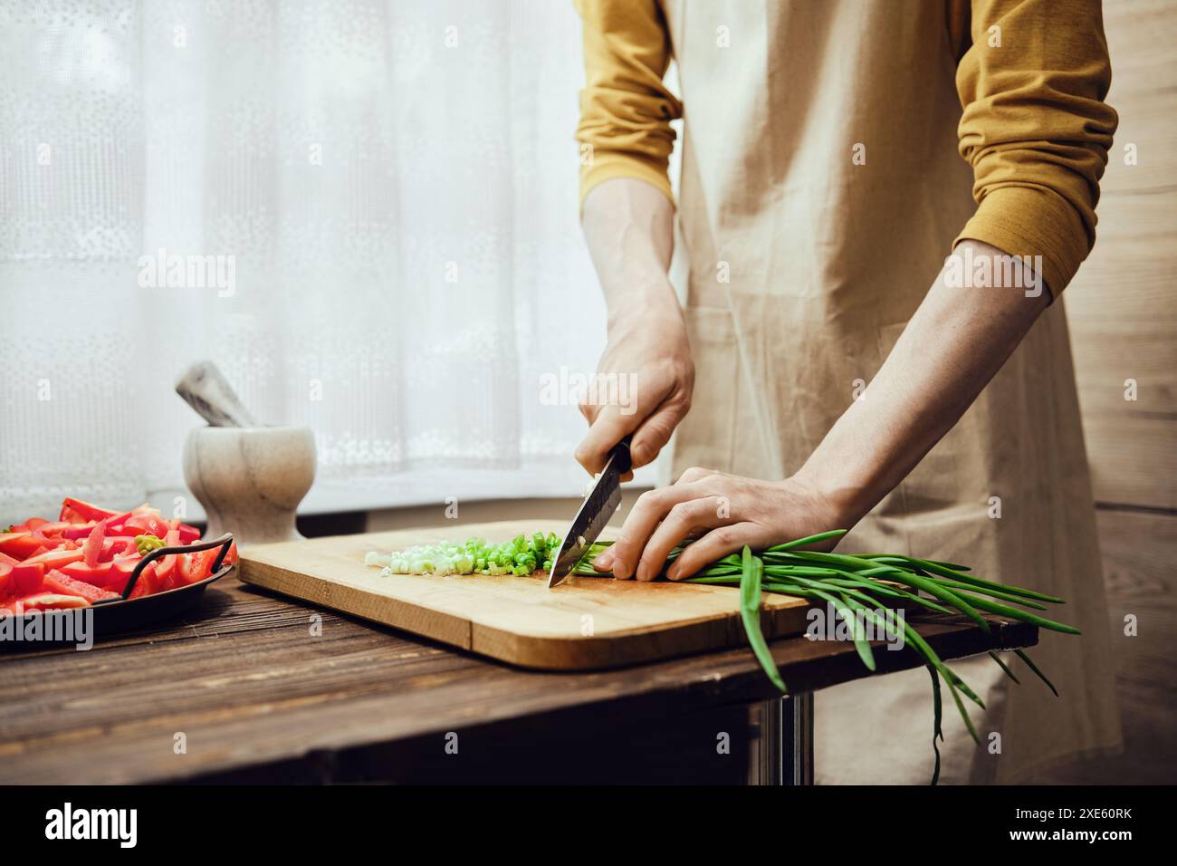 Unrecognizable man chopping fresh spring onion with kitchen knife in ...
