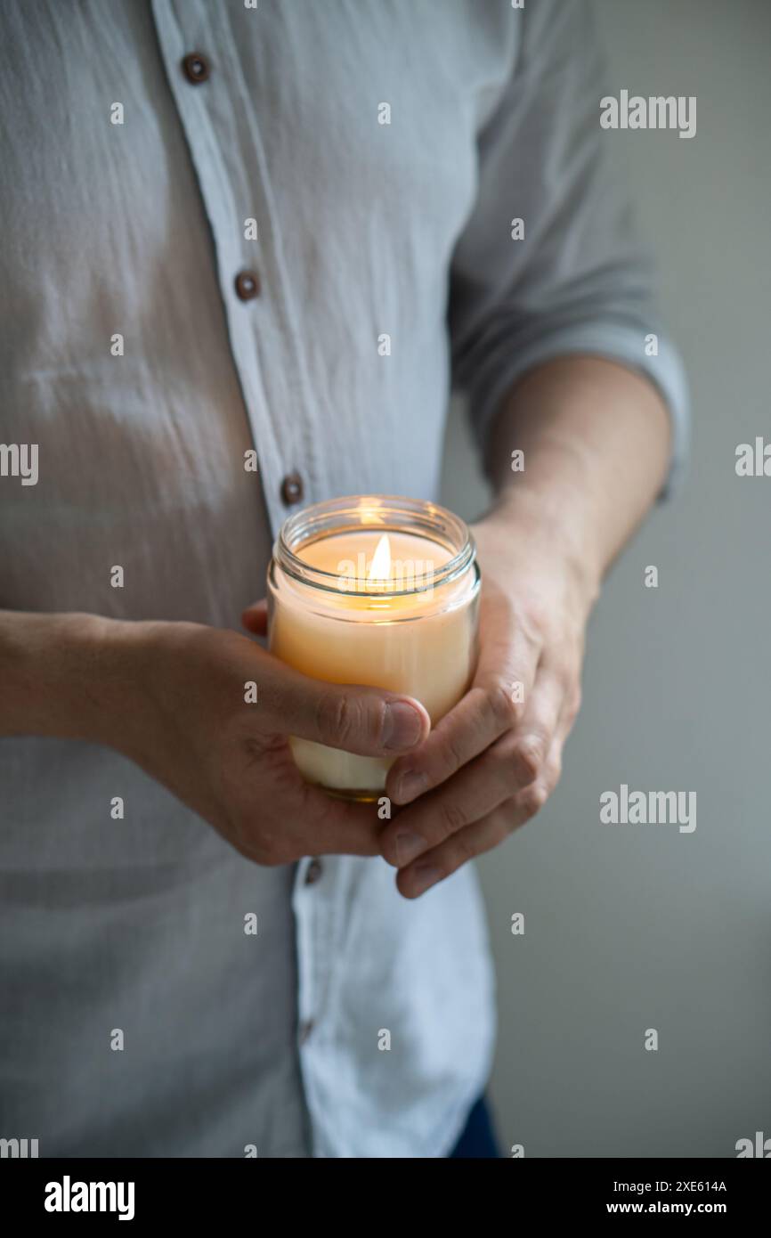 Man holding a burning candle in his hands, elegant young man with ...