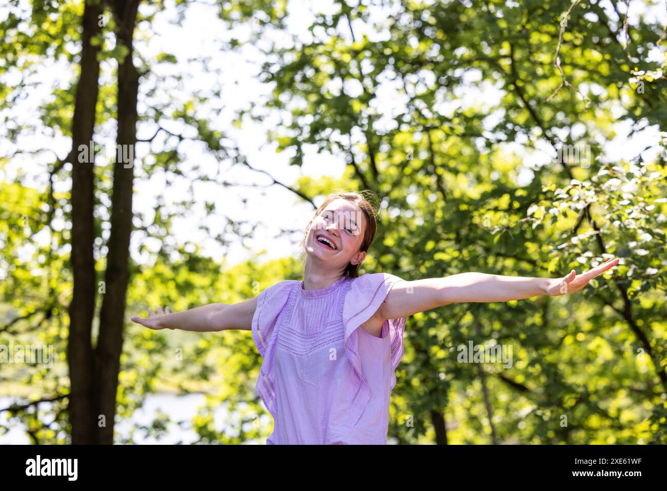 Exuberant Woman Embracing Nature in Sunlit Park Stock Photo - Alamy