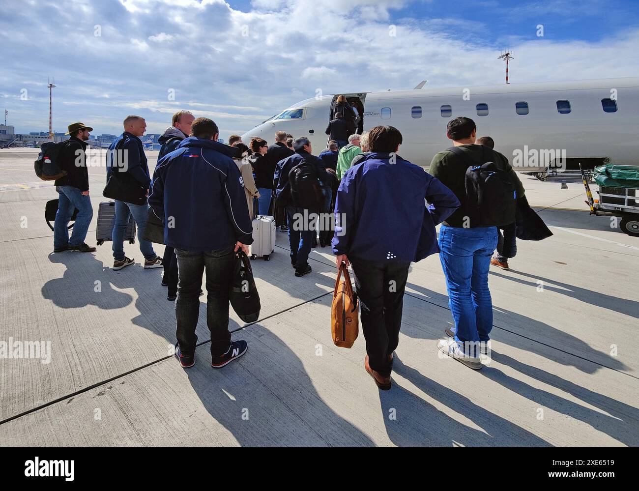 Passengers with hand luggage boarding a small plane on the tarmac ...