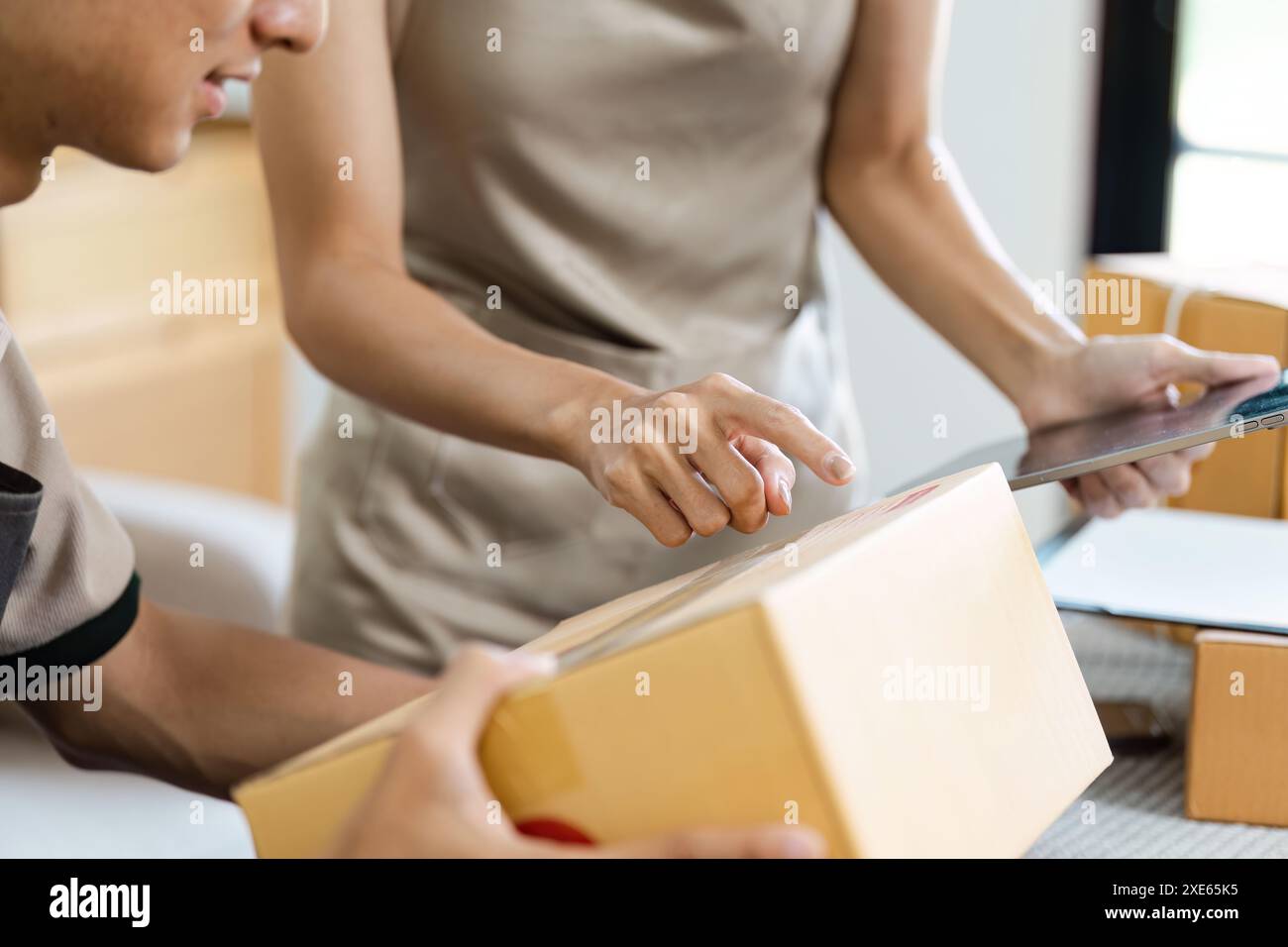 Small Business owner Managing order and Inventory Using Digital Tablet and Cardboard Boxes in ...