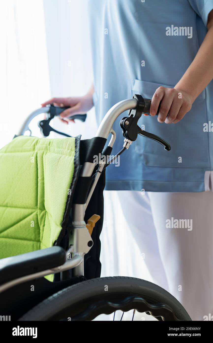 At the window Female medical worker pushing a wheelchair Stock Photo ...
