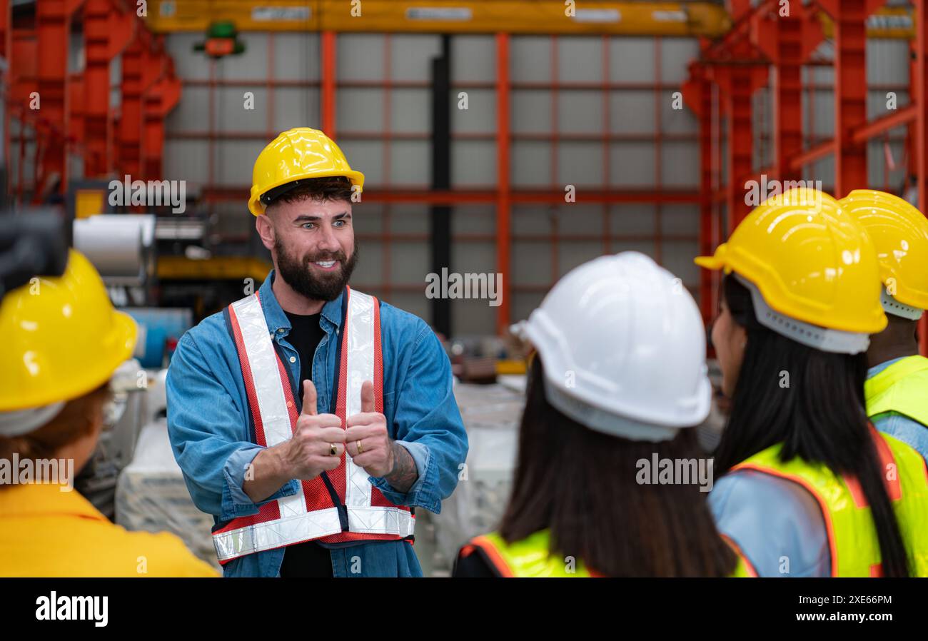 Supervisor and group of factory workers wearing hard hats meeting brief ...