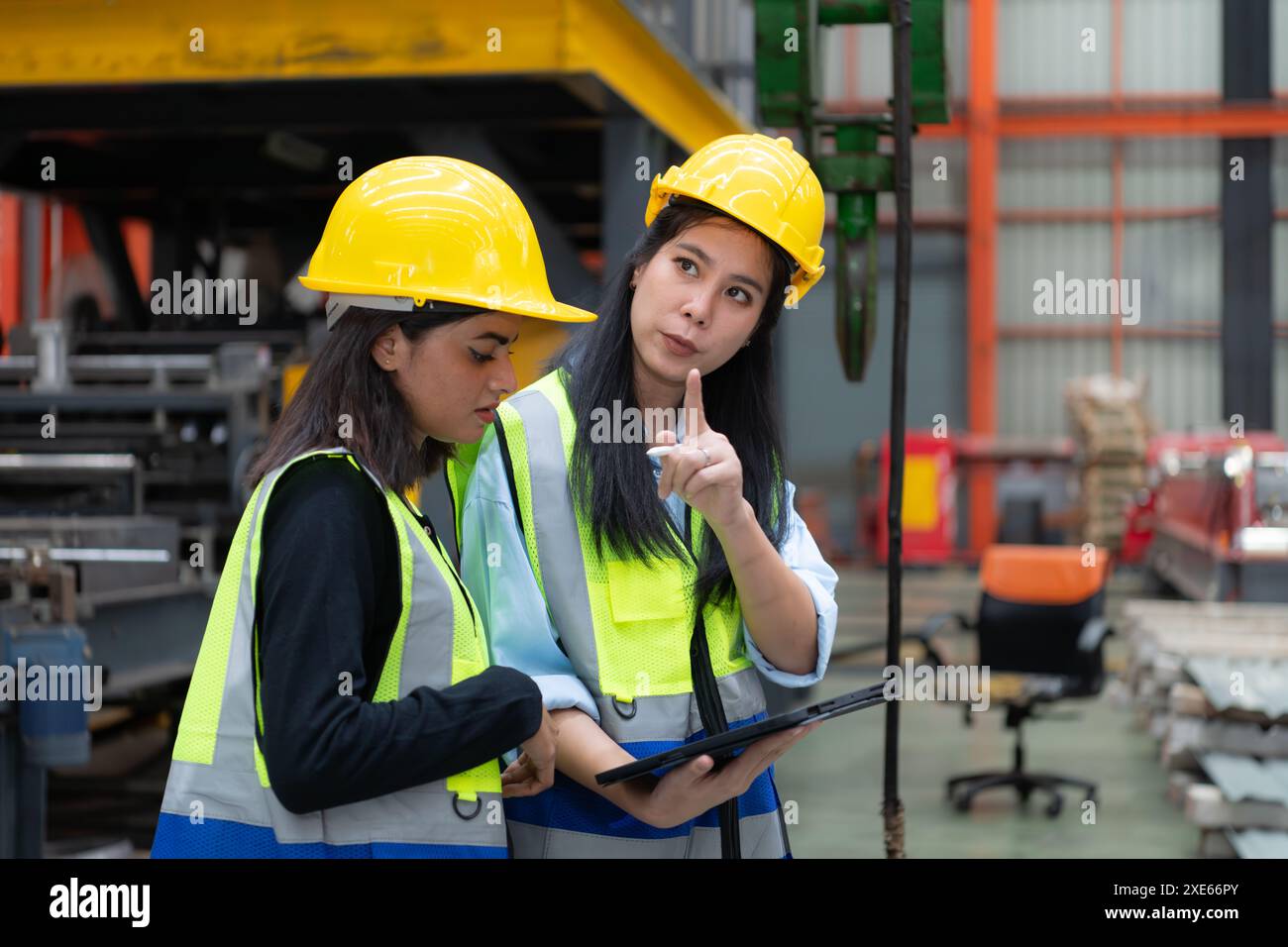 Two female engineers working together in metal sheet factory. This is a ...