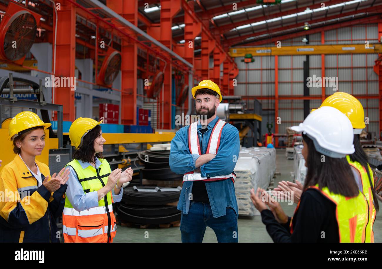 Supervisor and group of factory workers wearing hard hats meeting brief ...