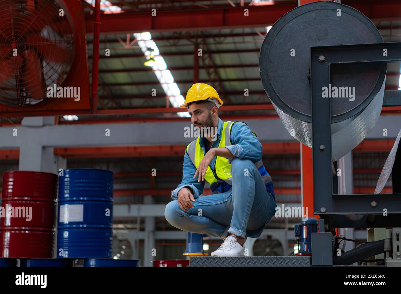 A young man works in a warehouse storing rolls of metal sheet material ...