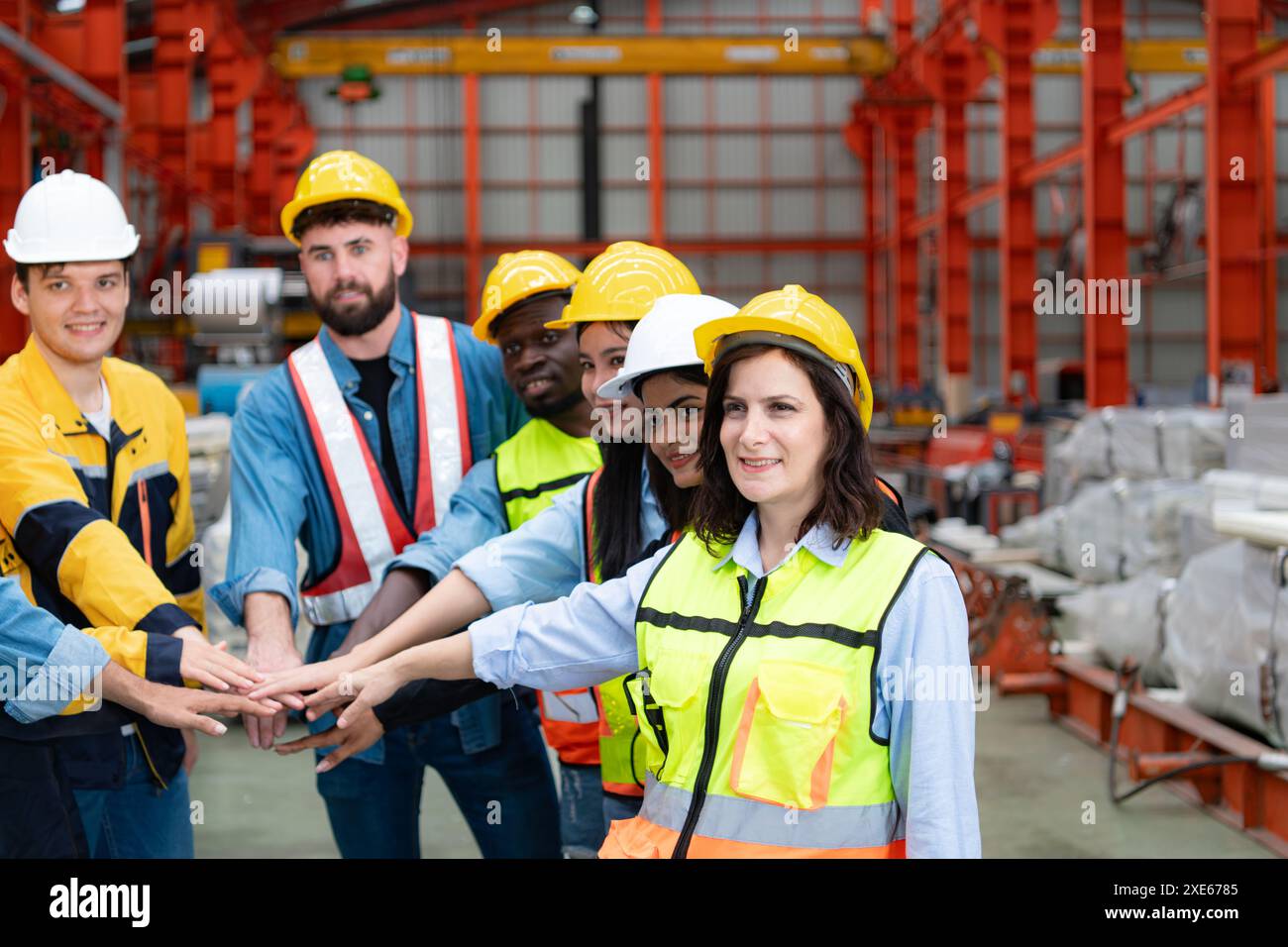 Group of factory workers in hardhats with joint hands together for celebrating success Stock ...