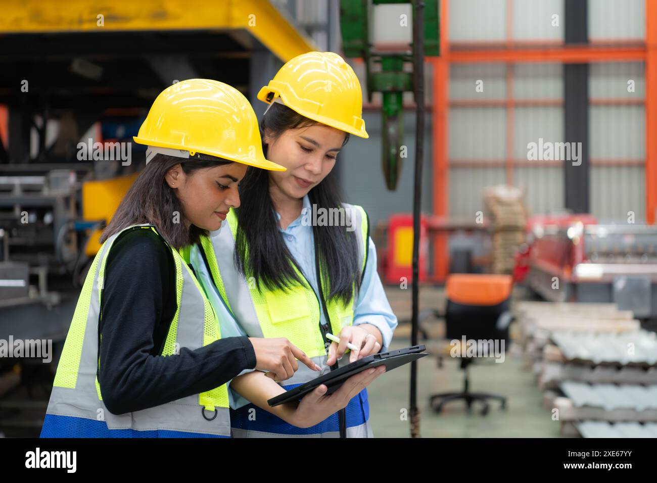 Two female engineers working together in metal sheet factory. This is a ...