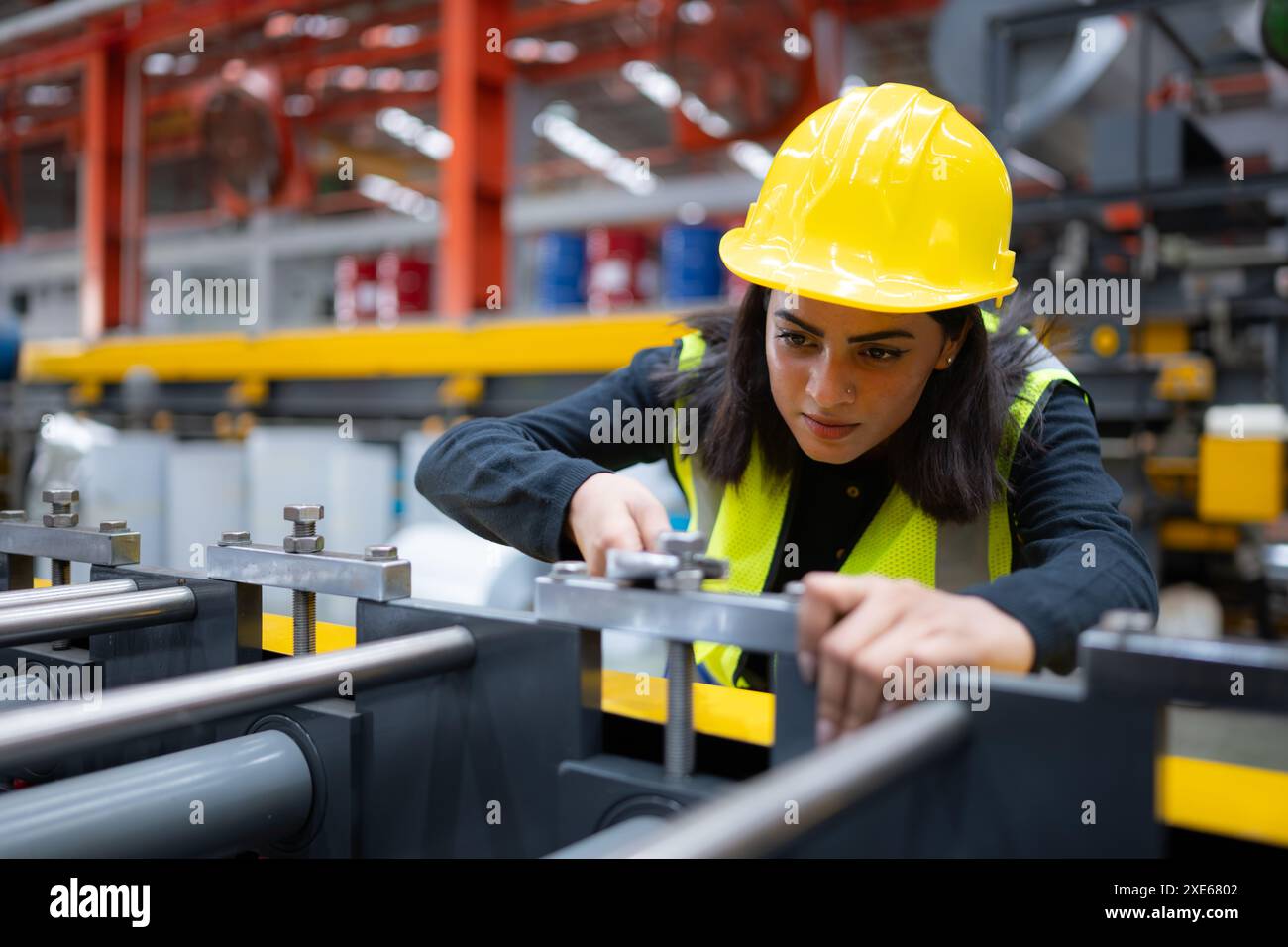 A female factory technician use a wrench to inspect the conveyor belt ...