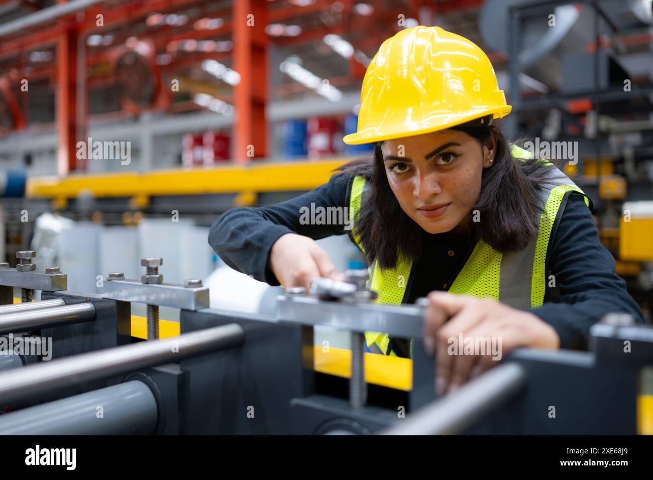 A female factory technician use a wrench to inspect the conveyor belt ...
