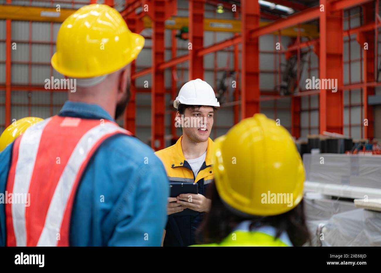 Supervisor and group of factory workers wearing hard hats meeting brief ...