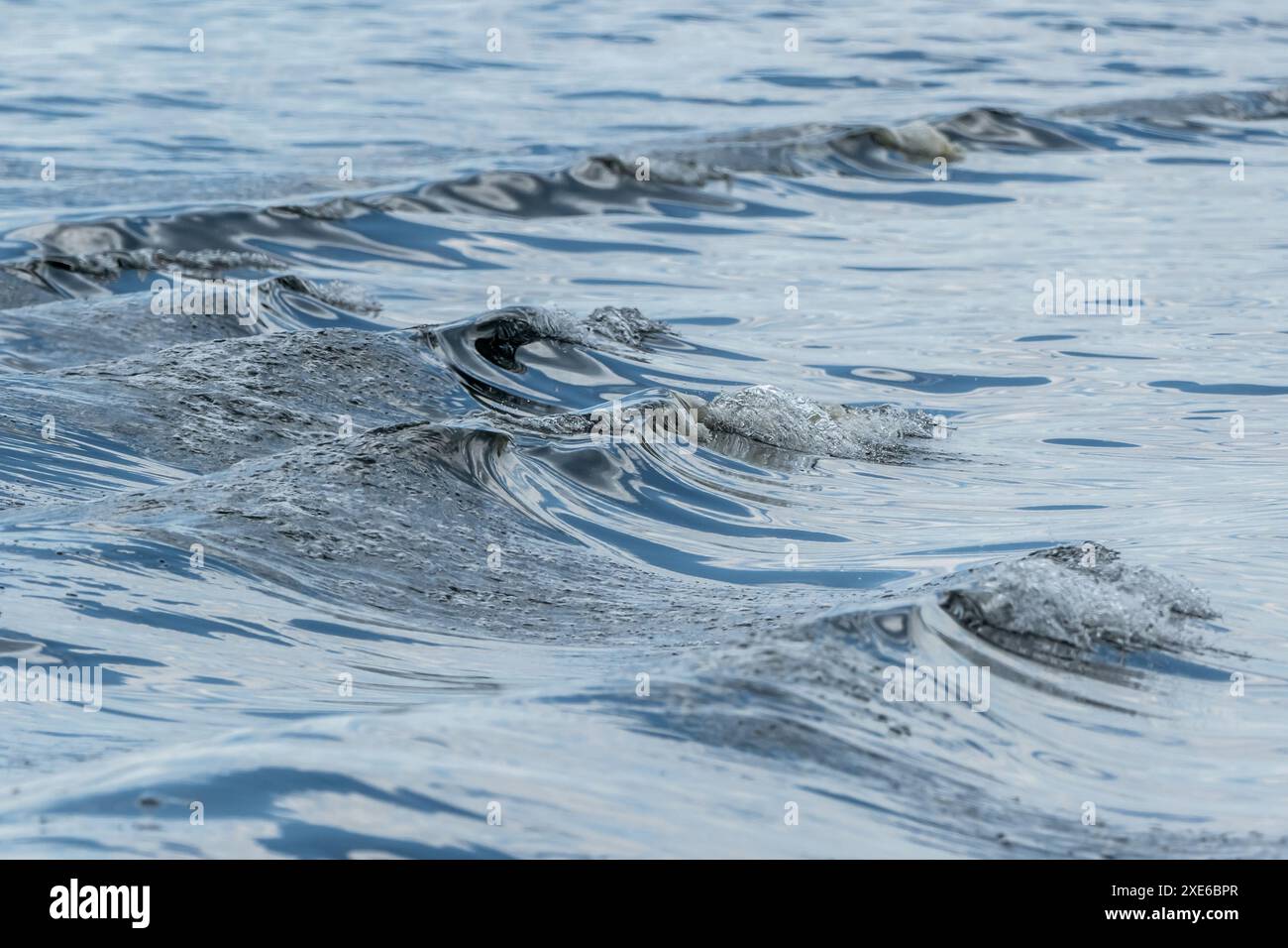 The wake of a boat travelling across the sea with small waves breaking ...