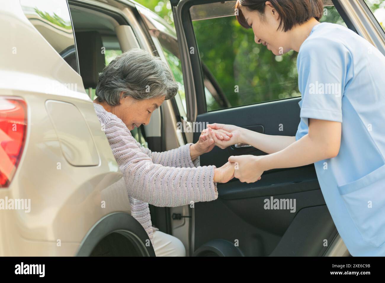 Female helper helping senior woman to get out of car Stock Photo - Alamy