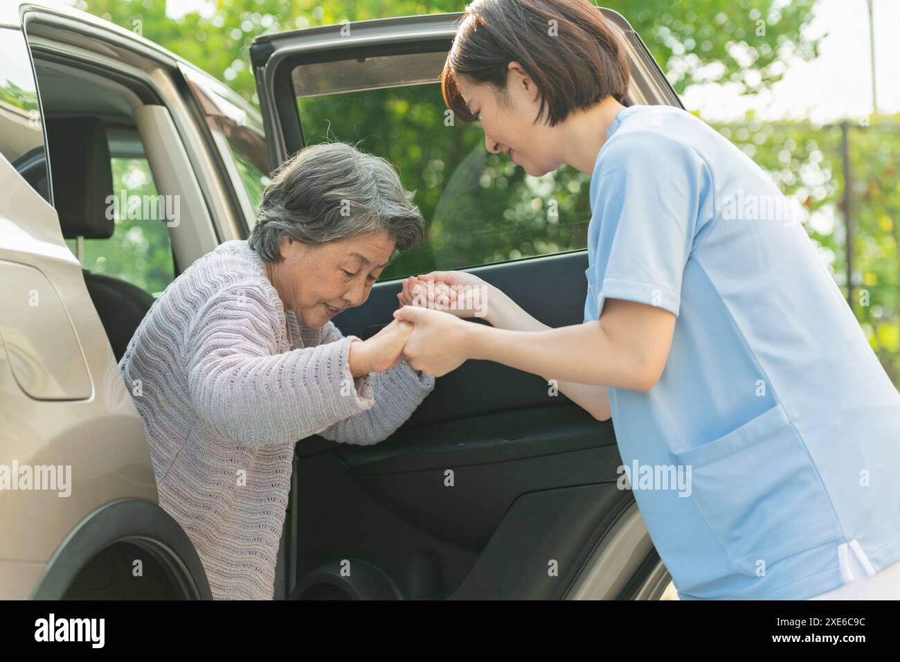 Female helper helping senior woman to get out of car Stock Photo - Alamy