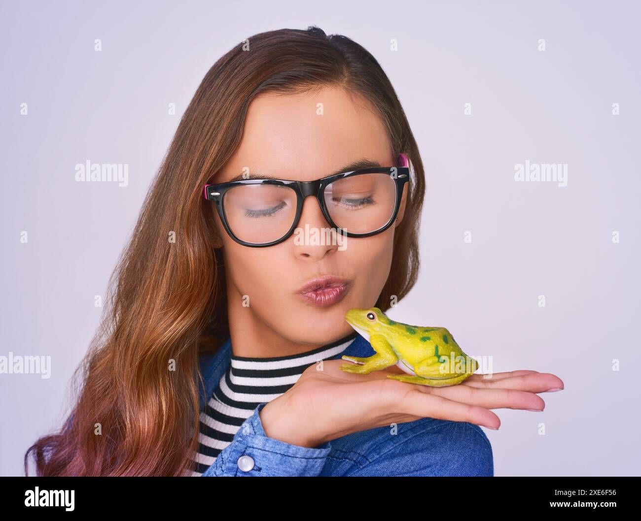 Beauty, woman and kiss frog in studio for fairytale transformation ...