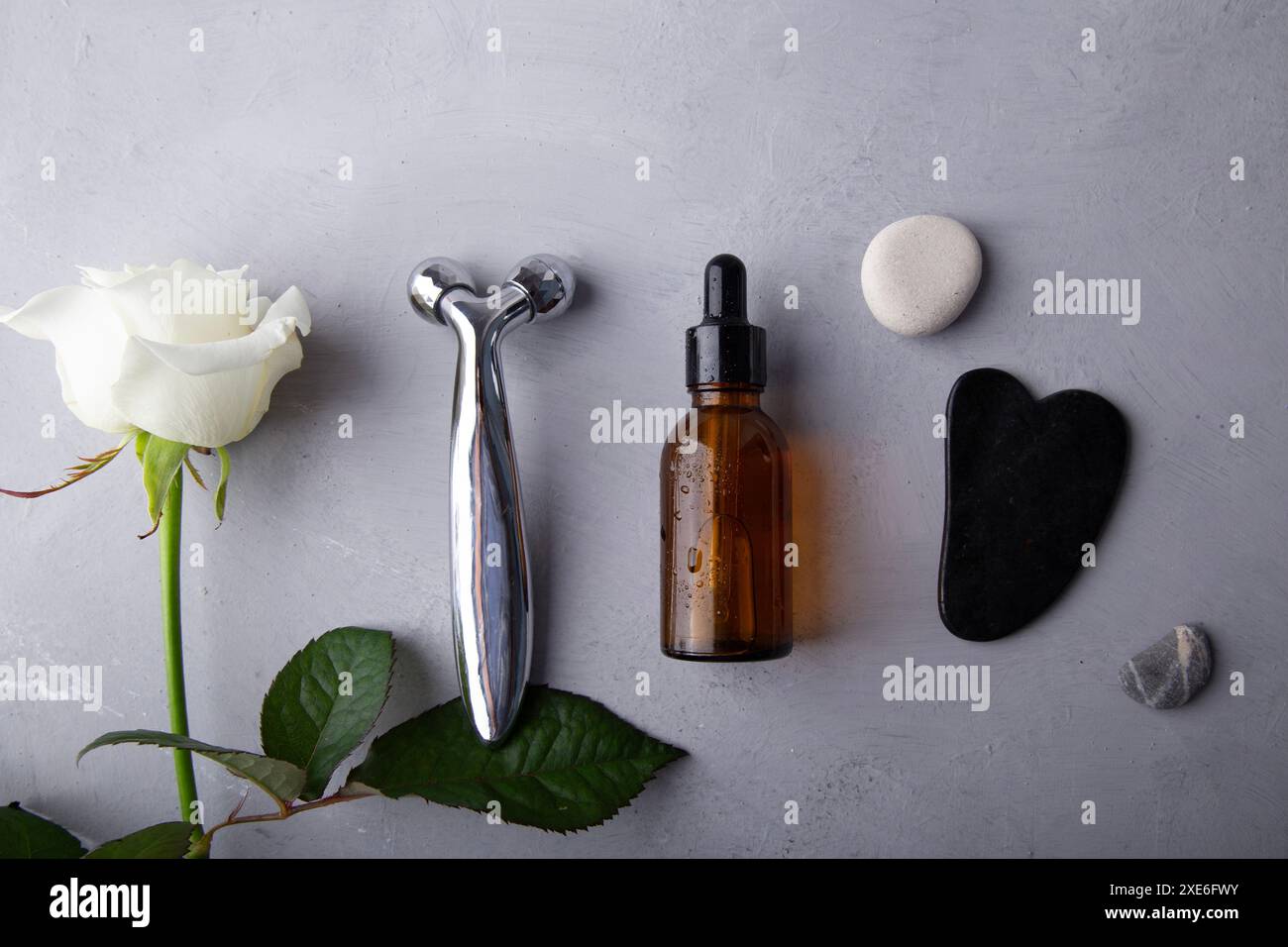 beauty essentials featuring fresh rose and facial massage tools on a ...