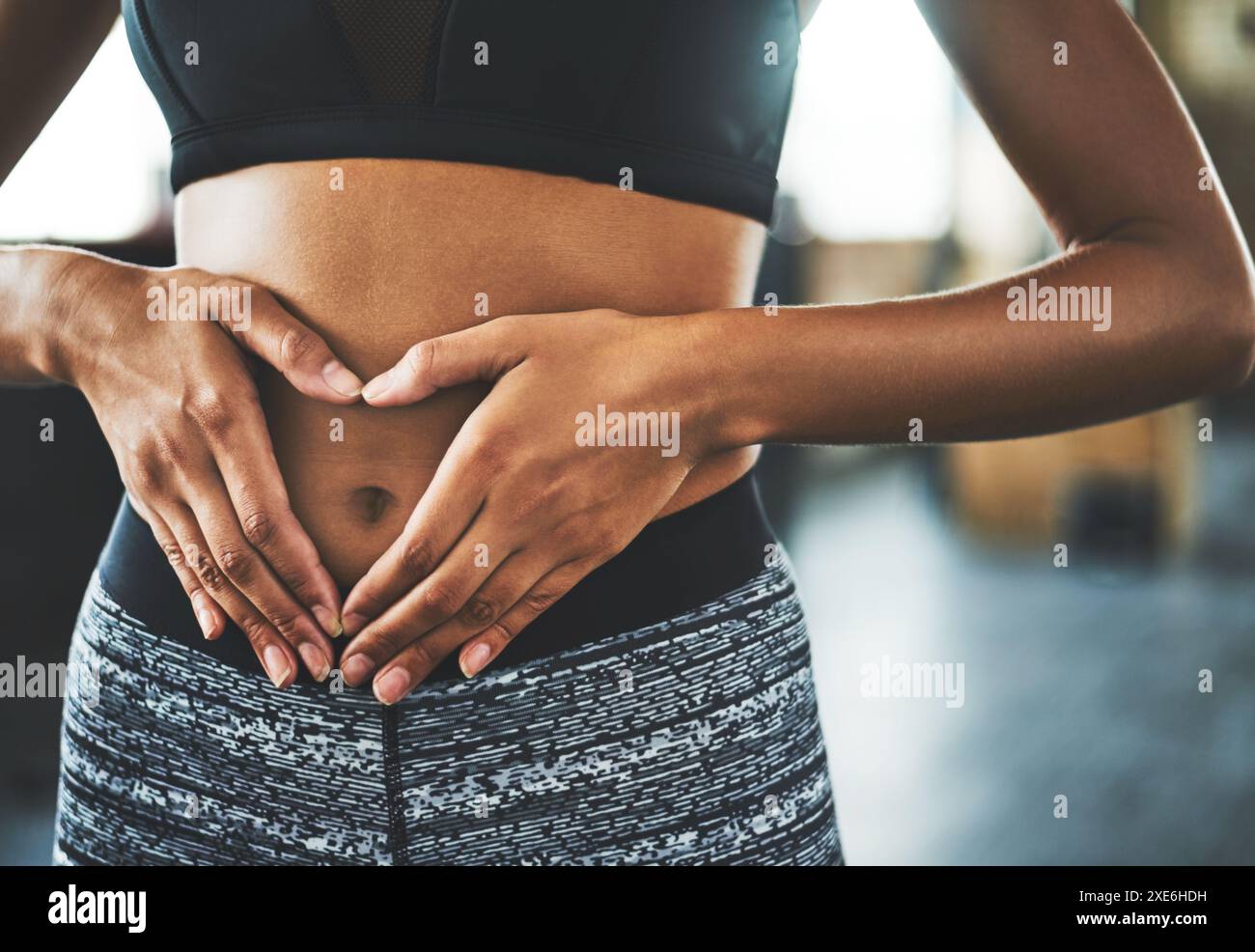 Health, digestion and hands on stomach for woman in gym, nutrition and ...